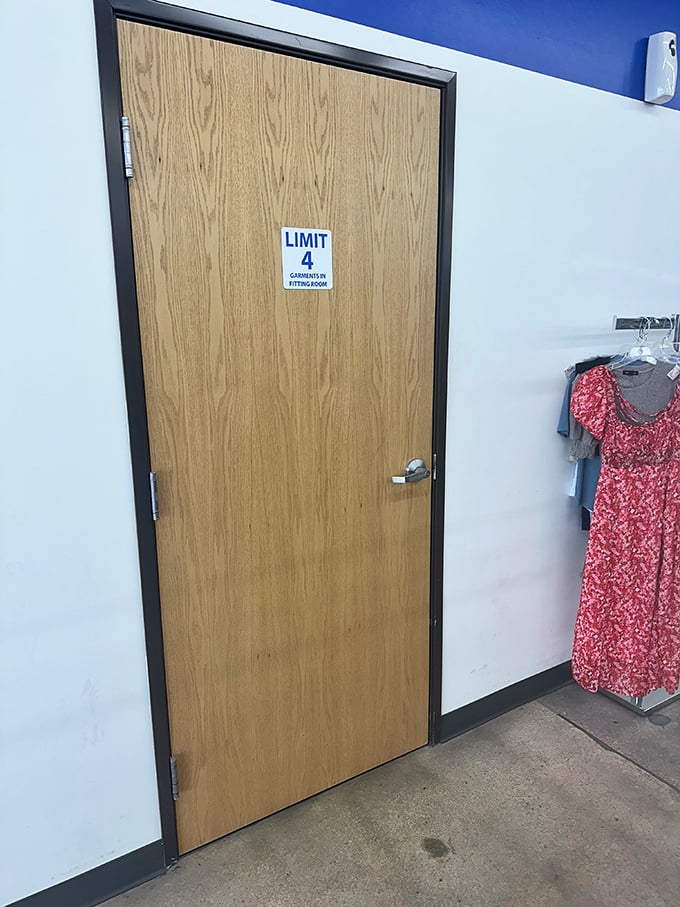 The fitting room door—gateway to possibility. Four garment limit means choosing wisely, like selecting contestants for a fashion reality show.