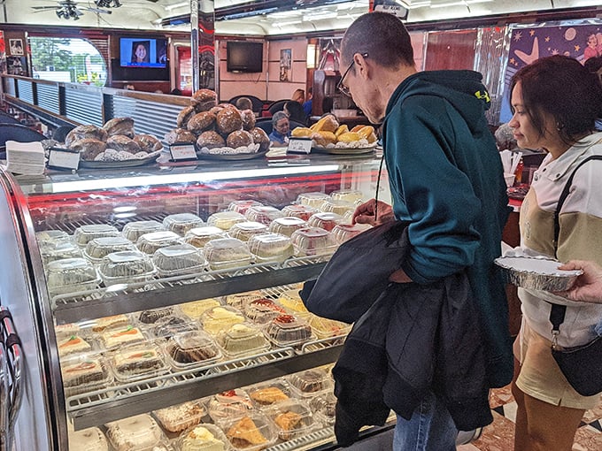 The pastry case—a glass-enclosed museum of temptation where willpower goes to die and "I'll just have coffee" becomes "and a slice of that."