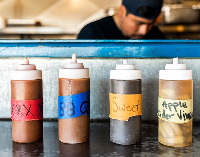 Barbecue sauce bottles lined up like soldiers ready for duty. Each one holds a different path to flavor nirvana – choose wisely, though they're all winning tickets in this sauce lottery.