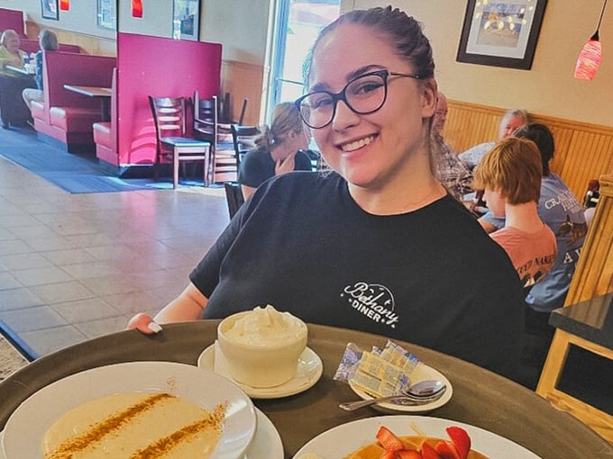 The smile says it all—service with genuine warmth. Fresh coffee being poured by someone who knows the regulars by name.