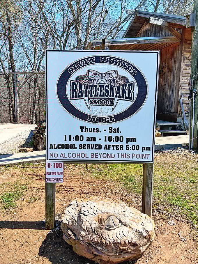 Operating hours posted with a rattlesnake sculpture guard—nature's way of saying "We're casual about most things, but punctuality isn't one of them."