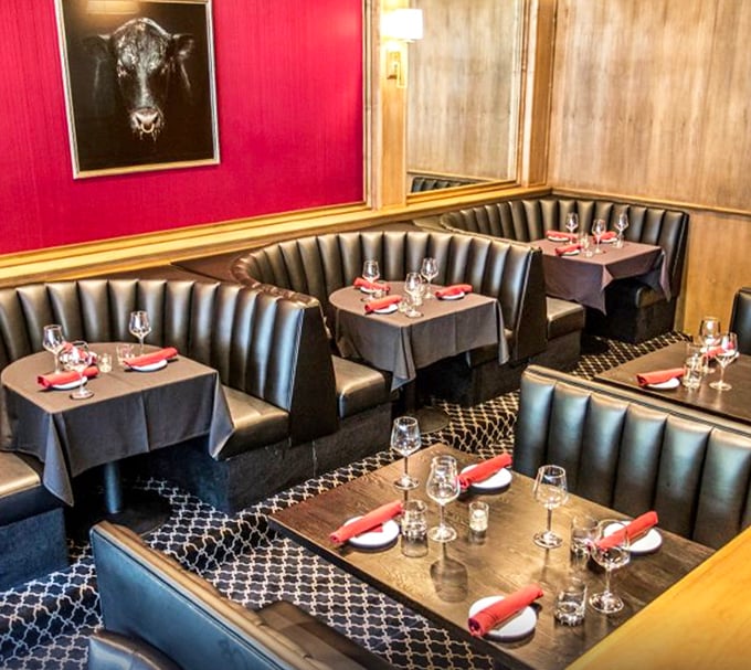 Red walls and curved booths create intimate dining spaces where deals are made, anniversaries celebrated, and diet plans temporarily forgotten.