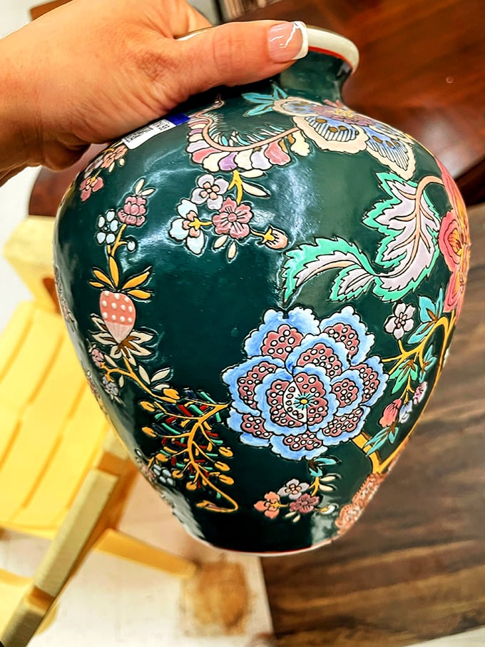 A hand cradles an intricately painted vase—someone's former treasure becoming your conversation piece. Floral artistry that never needs watering!