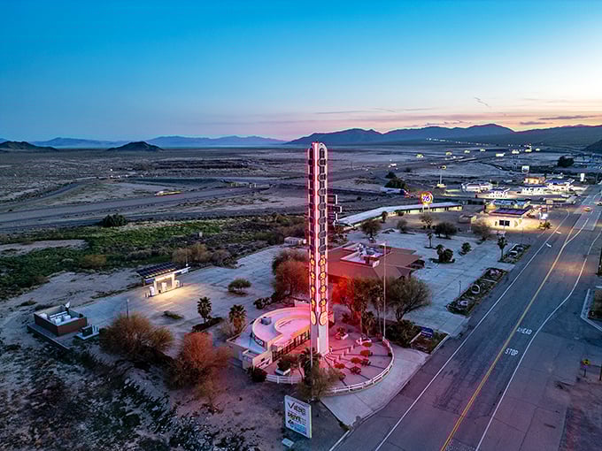 At sunset, the World's Largest Thermometer glows against the desert sky, a beacon for road-weary travelers.