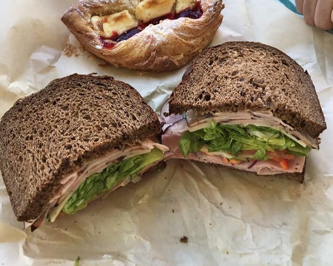 A sandwich so perfectly constructed it deserves architectural recognition—layers of ham, cheese, and veggies creating the skyscraper of lunch options.