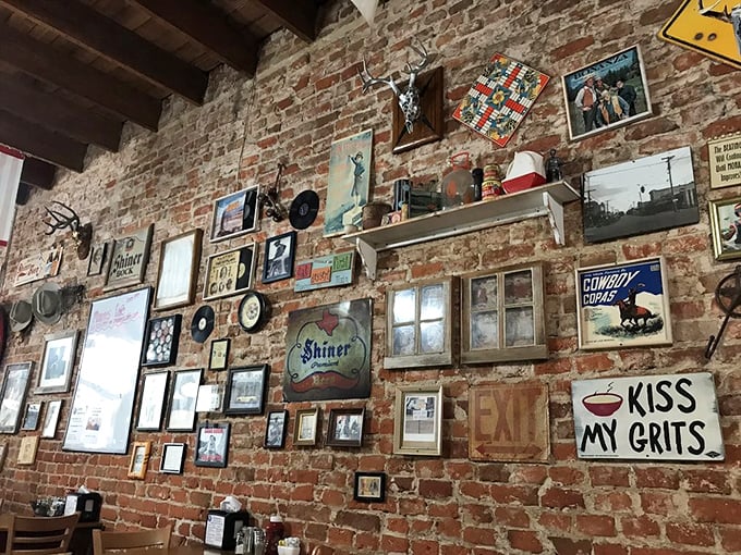 The wall doesn't just display decorations—it showcases Texas culture one frame at a time. That "Kiss My Grits" sign isn't just funny, it's a philosophy.