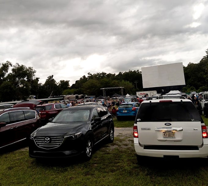 Cars gather under moody Florida skies as the iconic white screen awaits dusk's embrace – a scene unchanged since drive-ins first captured America's heart.