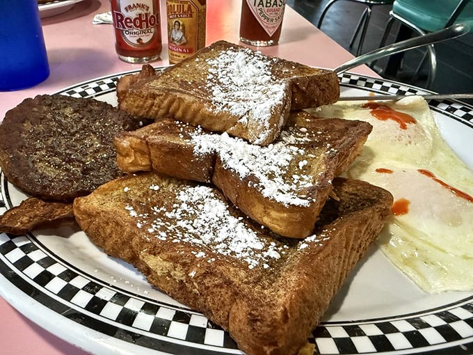 French toast stacked higher than your weekend expectations, dusted with powdered sugar like fresh snow on comfort food mountain.