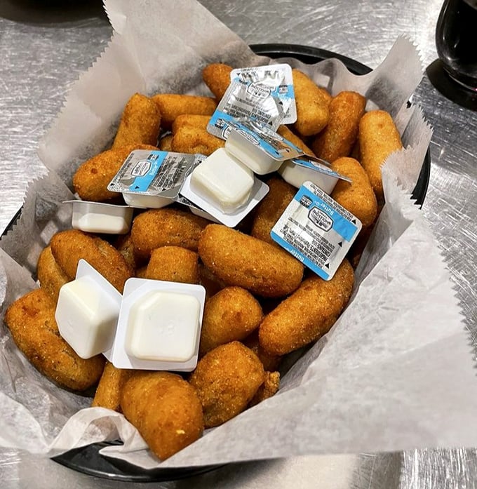 Golden hush puppies nestled in paper—crispy outside, tender inside. These aren't just side dishes; they're the supporting actors that steal the show.