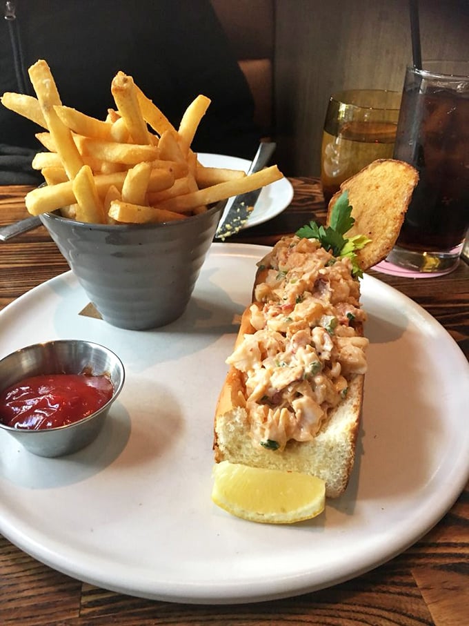 This lobster roll isn't messing around—chunky, fresh seafood barely contained by its buttery vessel, with fries standing at attention alongside.