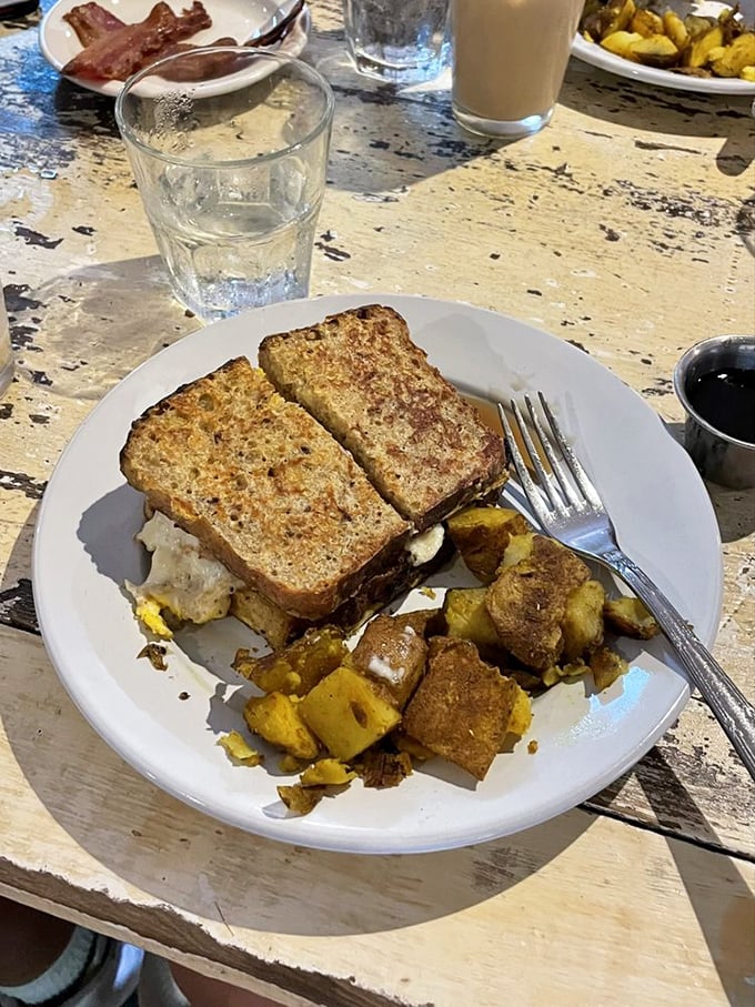 Breakfast sandwich perfection—golden-toasted bread hugging what appears to be eggs and cheese, with seasoned potatoes playing a delicious supporting role.