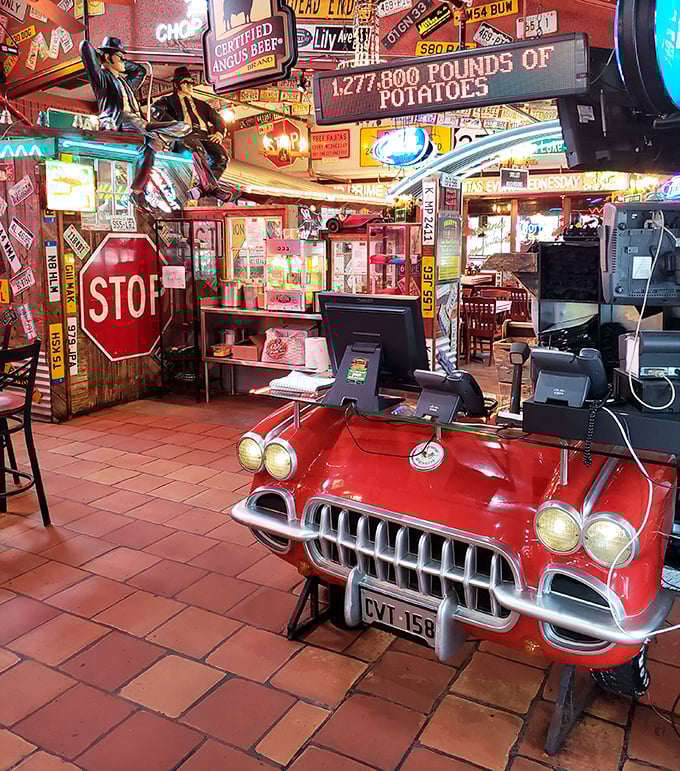 The front counter doubles as automotive memorabilia showcase—where a vintage Corvette front end serves as the perfect greeting station for hungry guests.