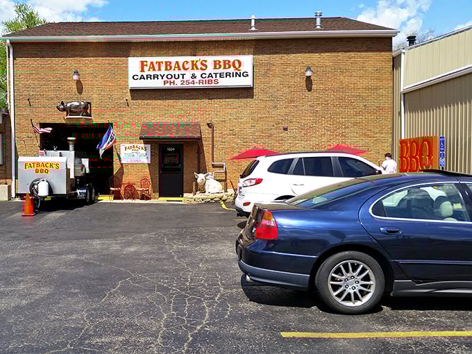 The parking lot view that signals you've arrived at your destination—where smoke signals and pig signs promise delicious things ahead.