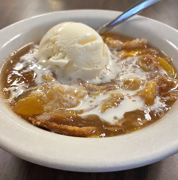 Peach cobbler topped with melting vanilla ice cream—where warm fruit meets cold cream in a dessert romance that's been making Texans swoon for generations.