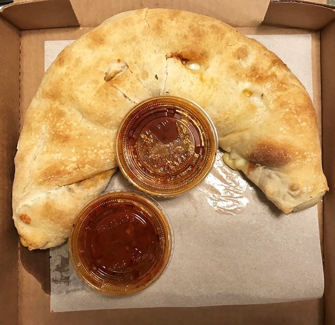 The calzone – pizza's mysterious, folded cousin. Two dipping sauces because important decisions shouldn't be made on an empty stomach.