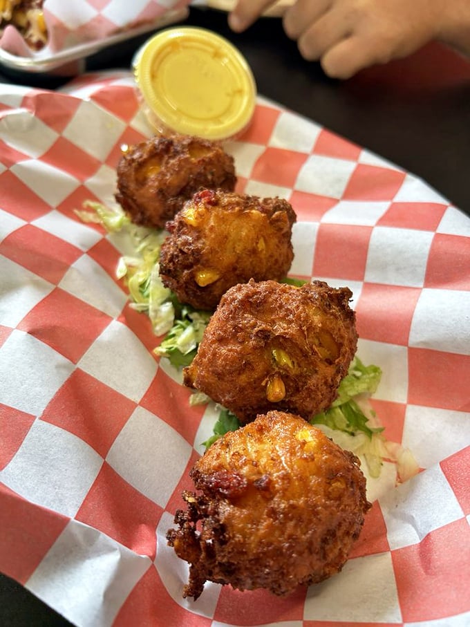 Golden-fried corn fritters studded with kernels of sunshine. These puppies aren't just pimped—they're royalty on a red-checkered throne.