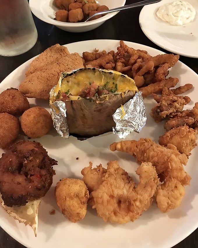 This plate is what happens when someone says "I'll have one of everything"—a glorious medley of fried seafood surrounding what appears to be a loaded baked potato.