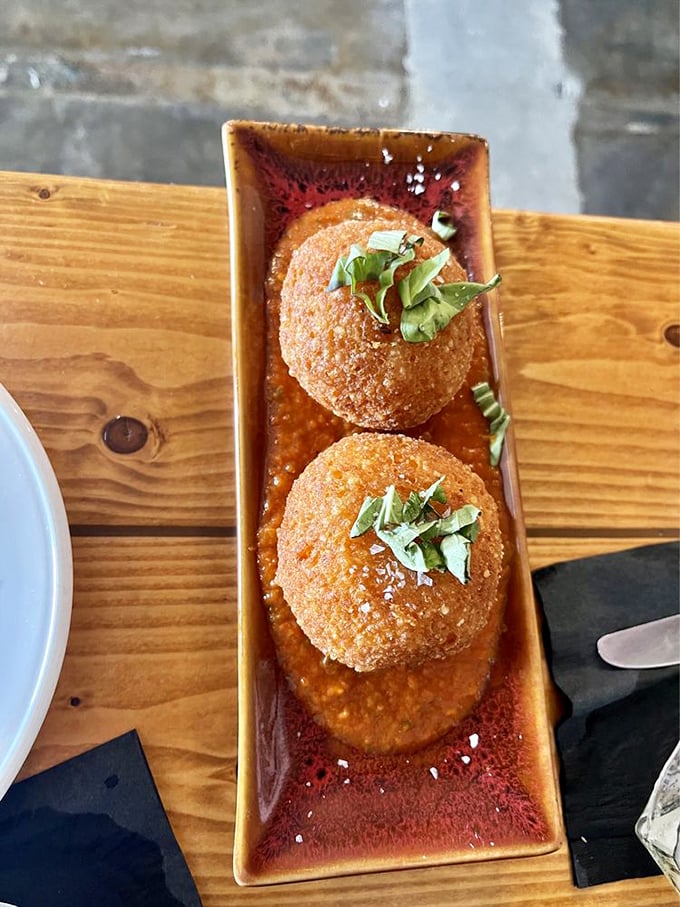 Golden orbs of risotto happiness. These crispy arancini balls sit in a pool of rich sauce, waiting to reveal their creamy secrets.