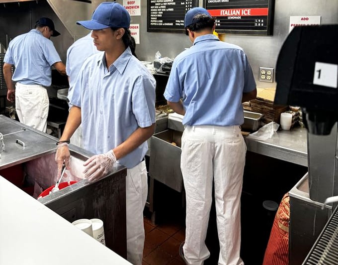 The uniform hasn't changed in decades: blue shirts, white pants, and the focused expression of sandwich artisans at work.