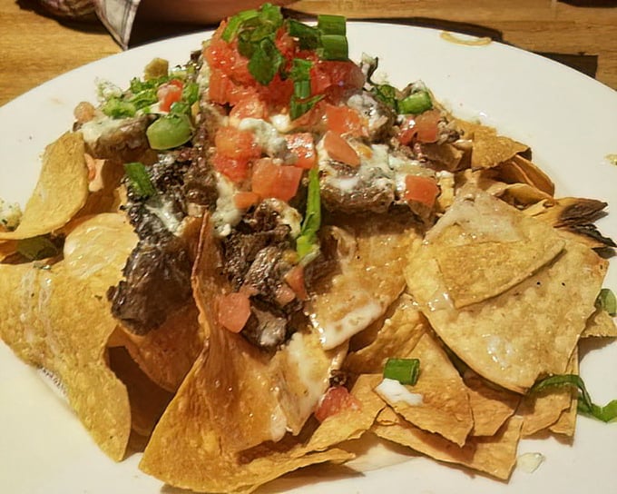 Nachos that laugh in the face of minimalism—a mountain of chips, cheese, steak, and toppings that requires a strategy session before diving in.