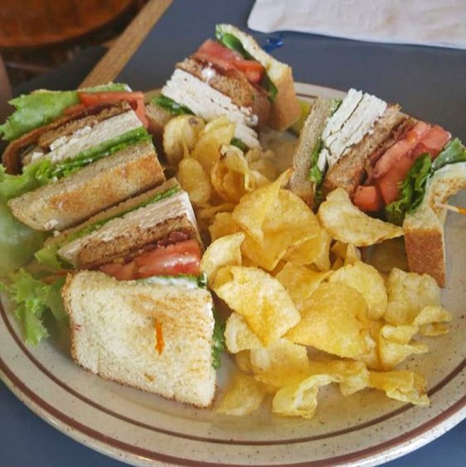 A club sandwich cut into perfect triangles with potato chips standing guard—the lunch equivalent of a warm hug on a plate.