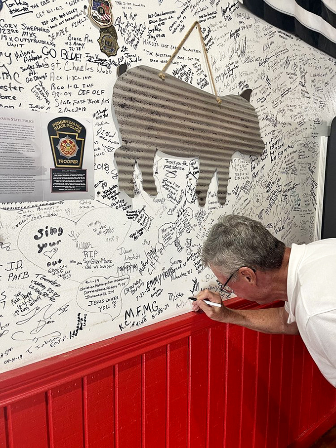 The signature wall where customers become part of BBQ history. Each signature tells a story of someone who came hungry and left transformed.