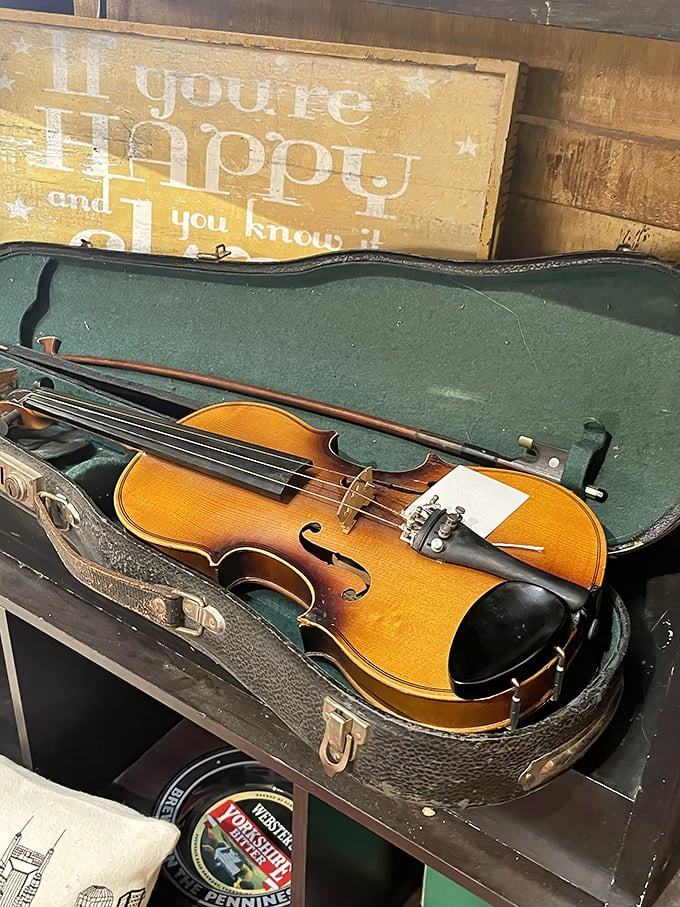 A violin rests in its case beneath a cheerful sign – both waiting for someone to make them sing again.