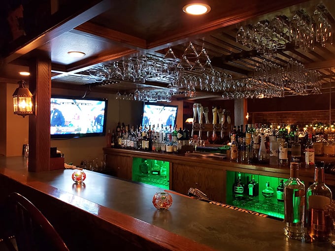 A bar that gleams with promise—hanging glasses catching the light like crystal chandeliers above that emerald-lit display.