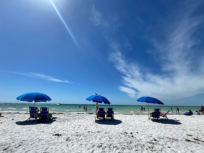 Three blue umbrellas standing guard over paradise. The beach chair rental that outperforms any five-star hotel lounger.