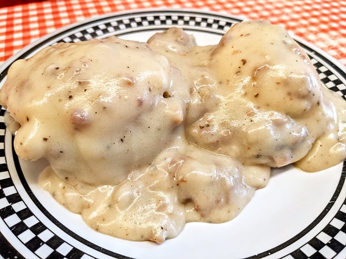 These biscuits and gravy aren't just breakfast—they're a warm, peppery hug on a checkered-rimmed plate.