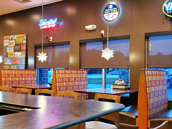 Colorful booth seating beneath neon beer signs – where the serious business of barbecue consumption happens in surprisingly comfortable surroundings.
