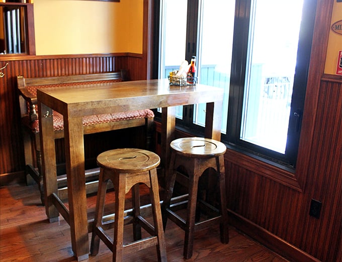 This cozy nook with its wooden high-top and stools isn't just seating – it's an invitation to linger over conversations that matter more than whatever's on your phone.