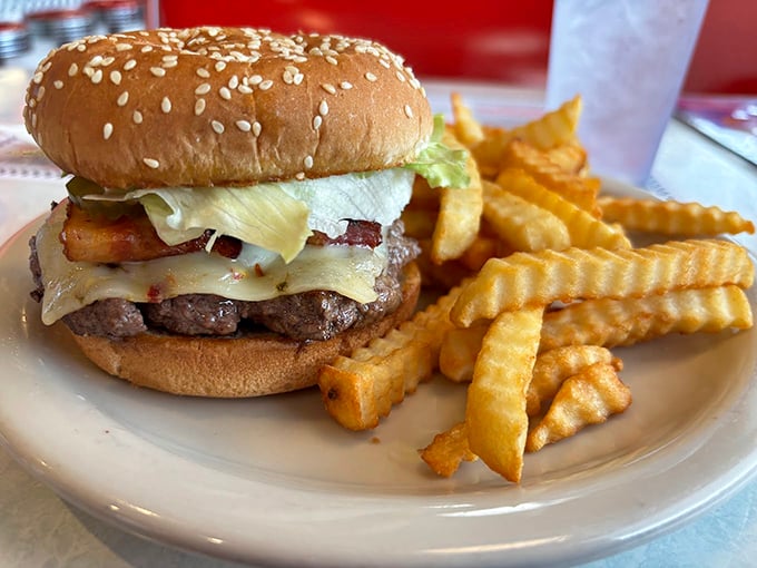 Behold the burger that time forgot – juicy beef, melty cheese, and bacon stacked on a sesame seed throne, with crinkle-cut fries as loyal subjects.