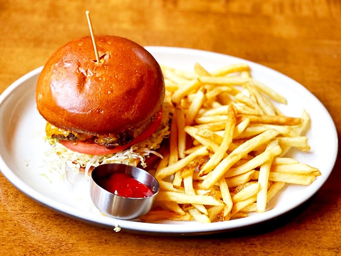 This isn't just a burger—it's architecture with a purpose, stacked tall on a glossy bun with fries standing by for the inevitable flavor overflow.