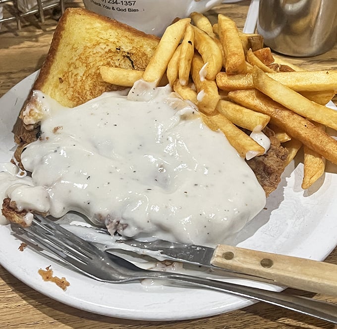 This chicken-fried steak sandwich smothered in country gravy isn't just comfort food—it's a warm, creamy hug on a plate with fries.