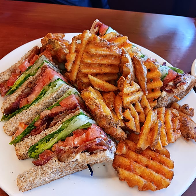 A club sandwich that's clearly overachieving, with waffle fries that refused to be ordinary – lunch making its case for attention.