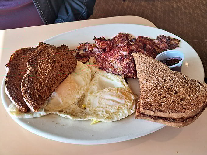 A breakfast plate that doesn't mess around—eggs, corned beef hash, and toast creating the holy trinity of morning satisfaction.