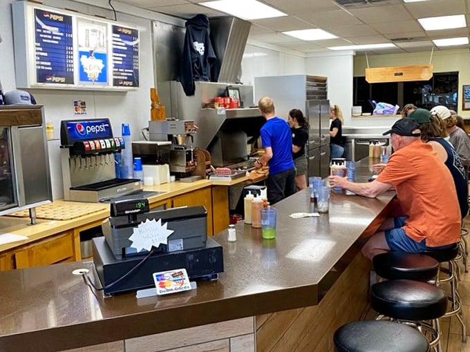 The counter view—where strangers become temporary friends united by the universal language of exceptional burgers.