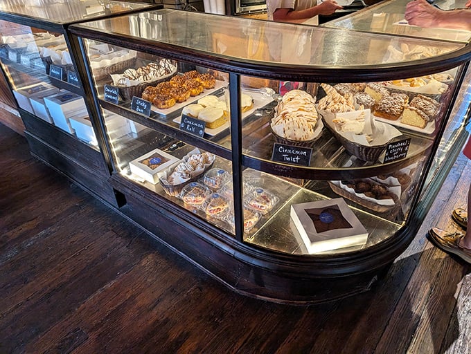 The display case—a glass-enclosed museum of edible art where willpower goes to die. Each shelf a new temptation, each pastry a new possibility.