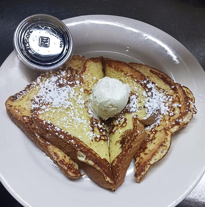 French toast that makes you question all other breakfasts—golden, custard-soaked perfection crowned with powdered sugar and a scoop of melting butter.