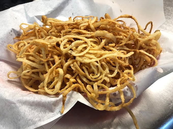 These aren't just onion straws—they're a crispy, golden tangle of happiness that somehow makes everything they touch taste better. Worth every calorie.