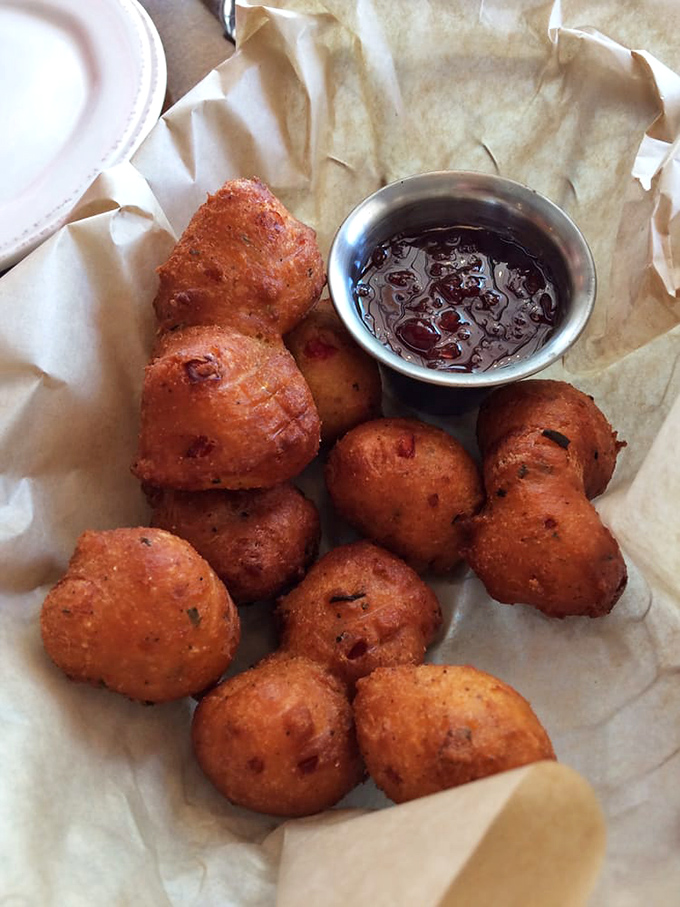 These hush puppies aren't just fried cornmeal—they're golden orbs of Southern tradition that demand to be dunked in that sweet dipping sauce.