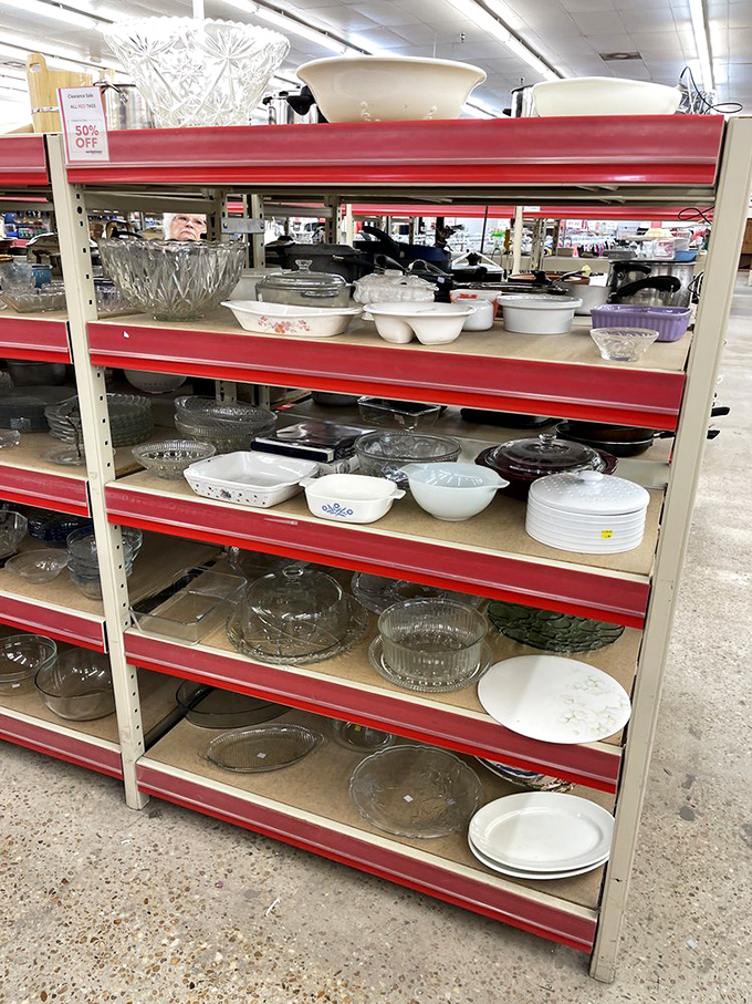 Kitchen essentials line red shelves like a culinary variety show, from crystal bowls to everyday casserole dishes.