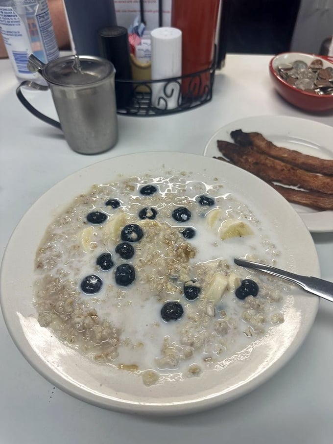 Oatmeal elevated from punishment to pleasure with blueberries standing by like tasty little sentinels. Those bacon strips aren't just sides – they're essential companions.