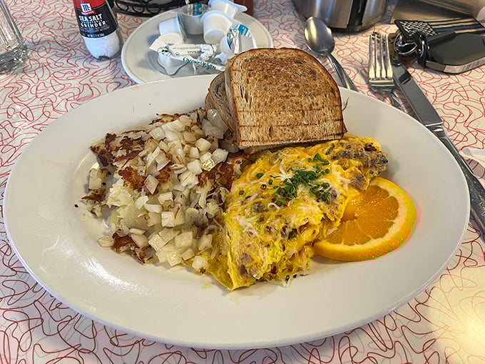 This omelet arrives loaded with fillings and possibilities, accompanied by perfectly crisped home fries demanding immediate attention.