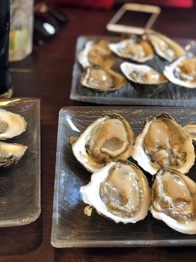 Fresh oysters glisten like jewels on their slate throne. These briny treasures from nearby waters need nothing more than a squeeze of lemon and appreciative sighs.