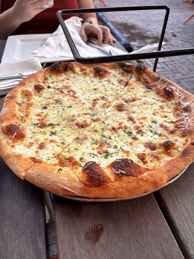 The white pie isn't playing second fiddle to its red sauce siblings—it's conducting its own symphony of garlic, herbs, and cheese.