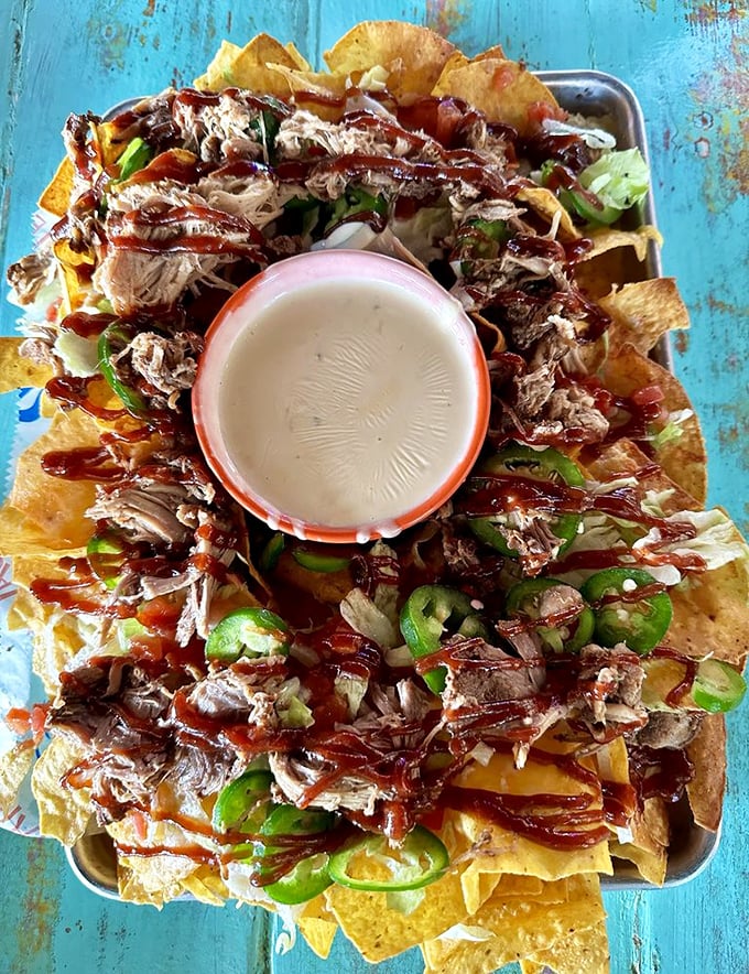 Nachos that refuse to be ordinary—crispy chips loaded with pulled pork, jalapeños, and enough toppings to require a strategic eating plan.