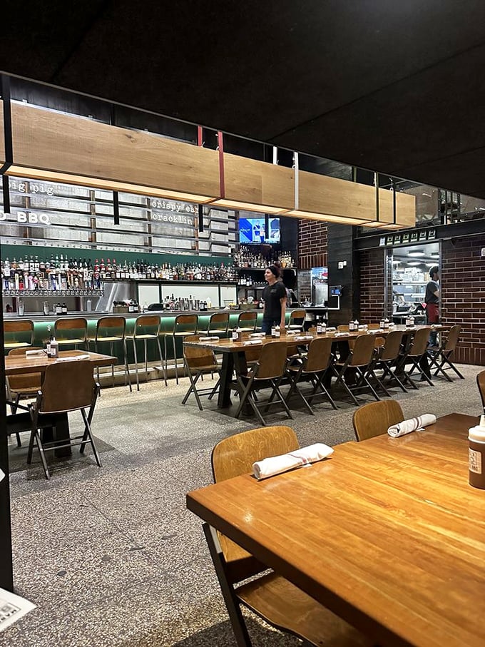 Wooden chairs and tables await the next round of barbecue pilgrims, while the bar's green glow promises libations worthy of the meat masterpieces to come.