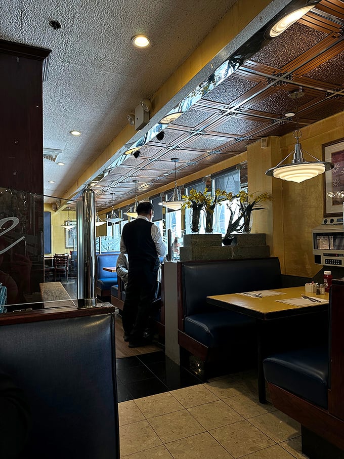 Warm lighting bathes leather booths in golden ambiance while a server stands ready—the scene could be from any decade of the last fifty years.